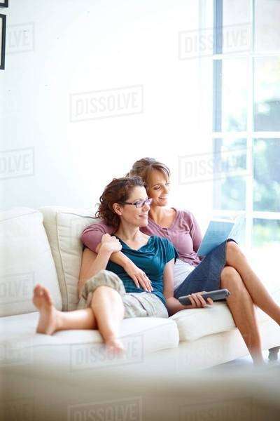 Two women cuddling on sofa - Royalty-free Stock Photo | Dissolve