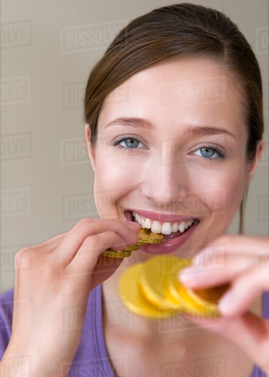 Woman bites on gold coins - Royalty-free Stock Photo | Dissolve
