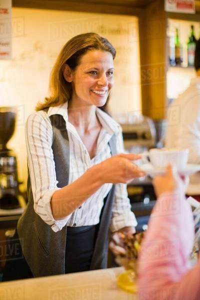 Woman serving coffee in cafÃ© - Royalty-free Stock Photo | Dissolve