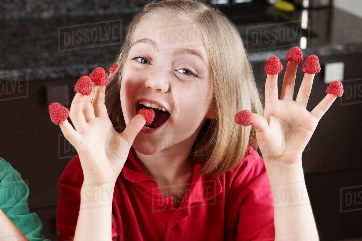 Girl with raspberries on fingers - Royalty-free Stock Photo | Dissolve