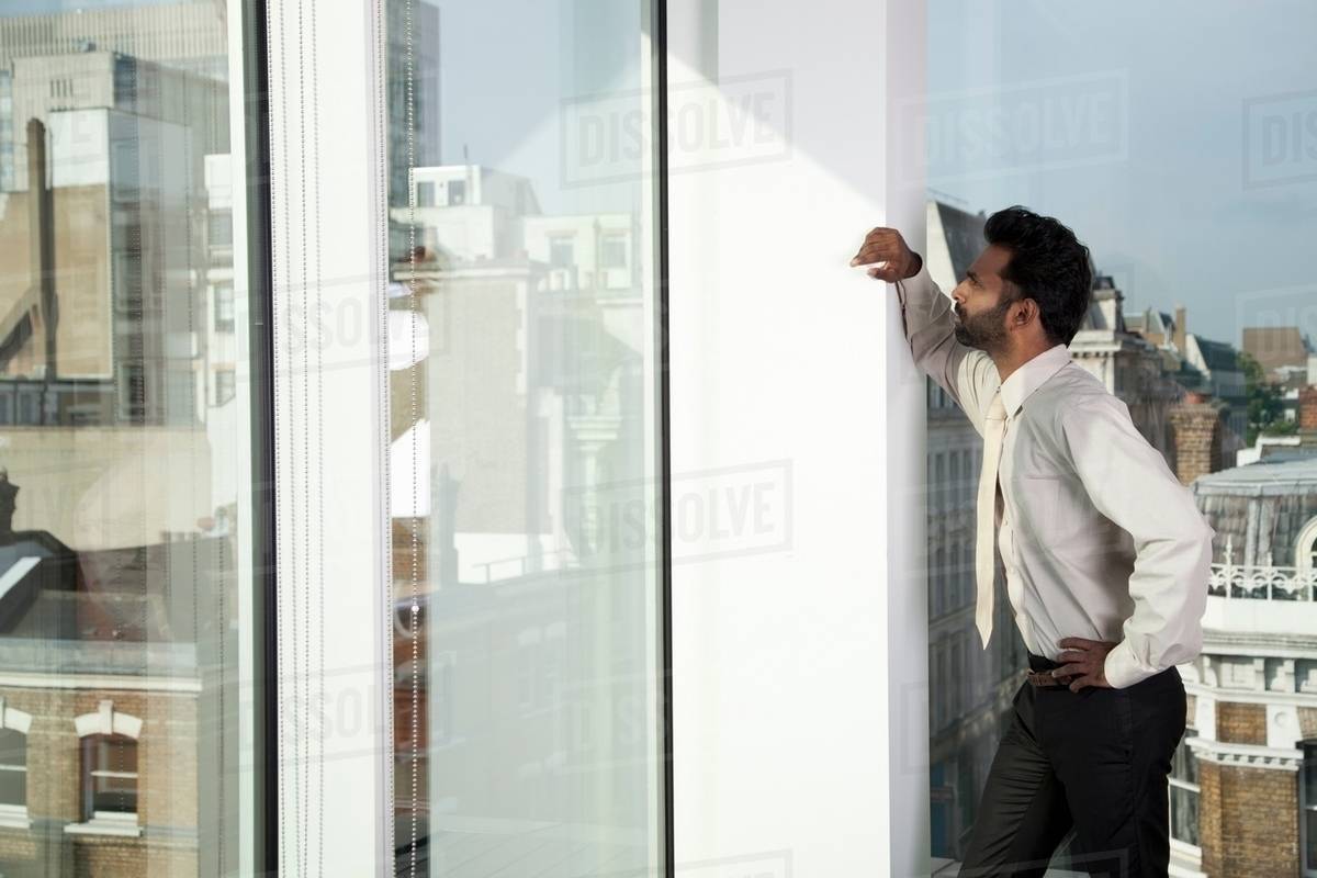Businessman looking out of office window - Stock Photo - Dissolve