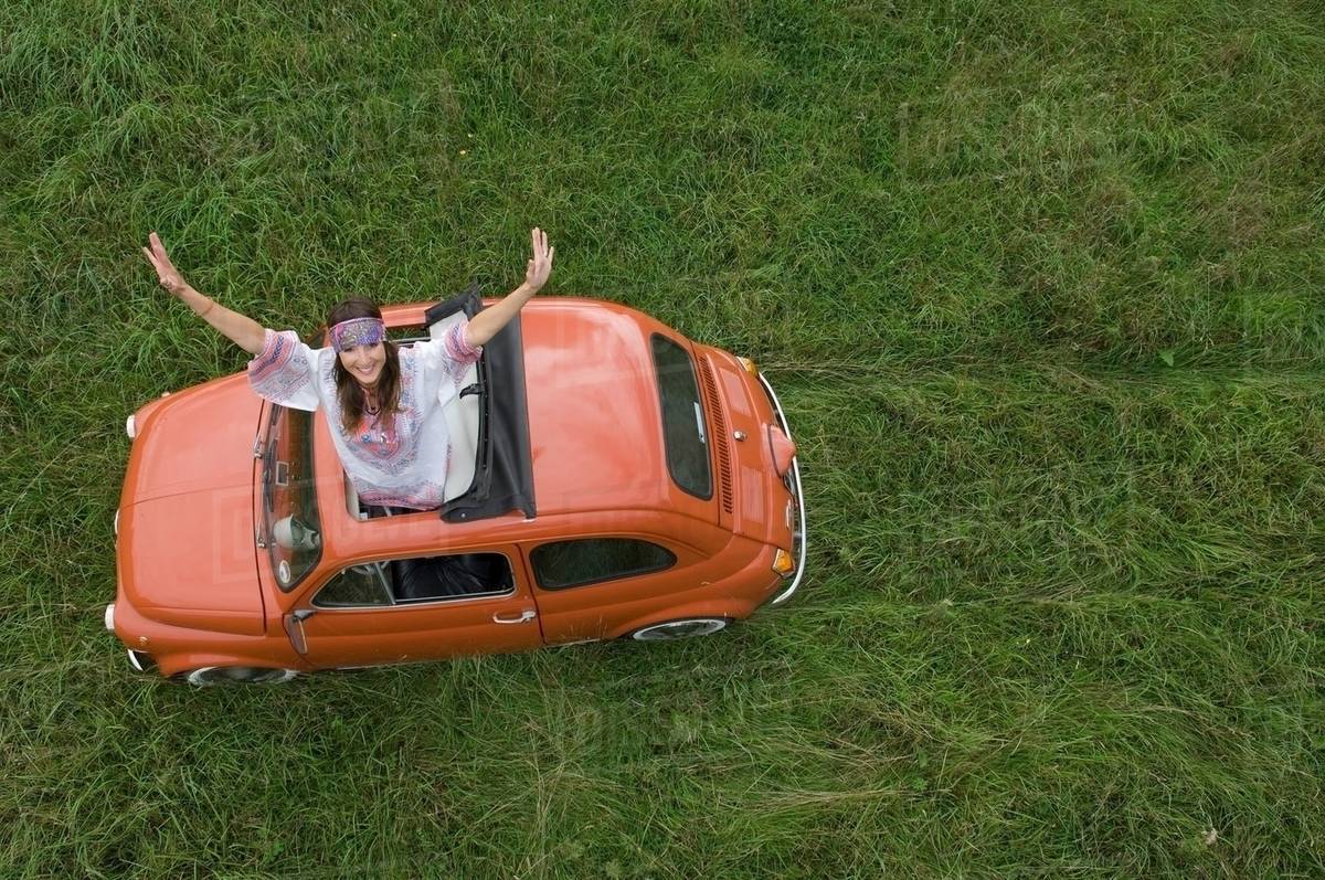 Hippy female stretching out of car - Stock Photo - Dissolve