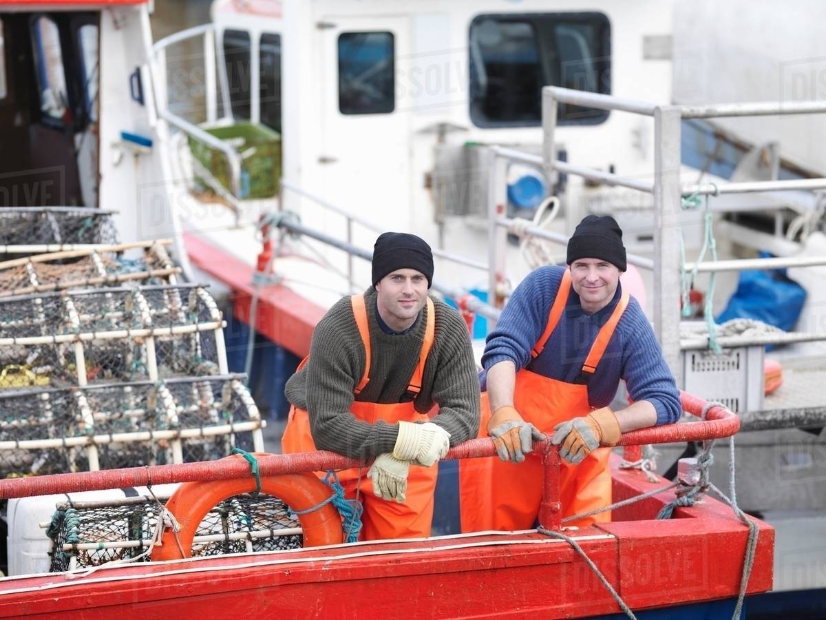 Fishermen on boat in harbour - Stock Photo - Dissolve