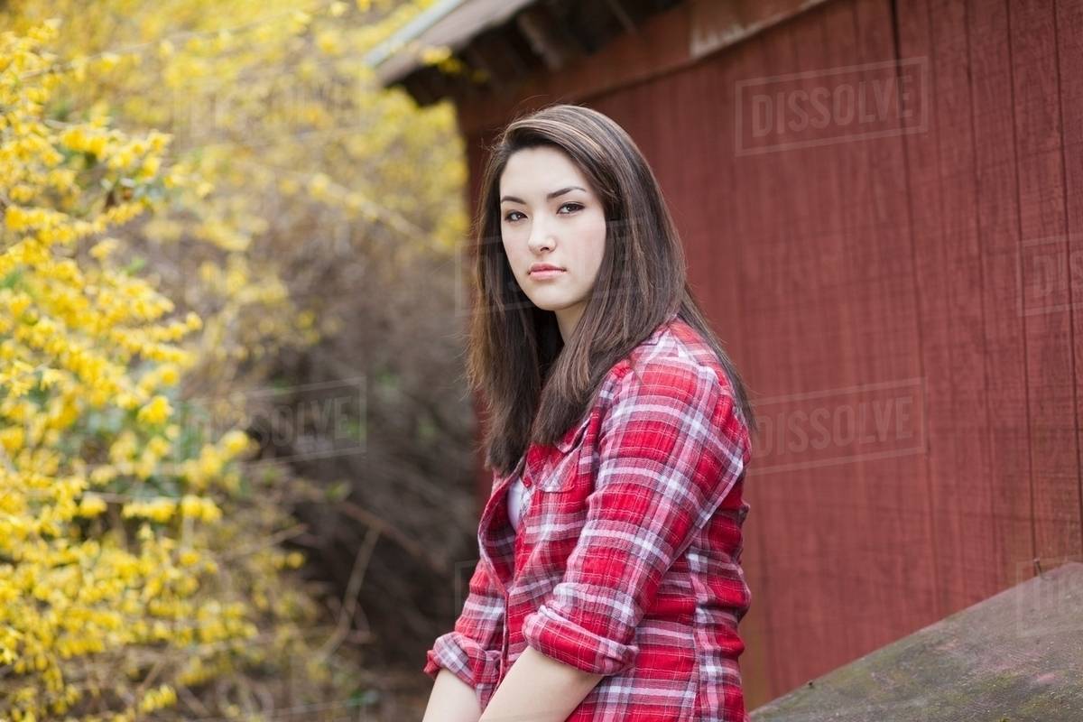 Girl sitting in front of barn - Stock Photo - Dissolve
