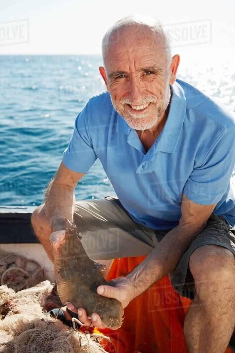 Fisherman holding fish - Stock Photo - Dissolve