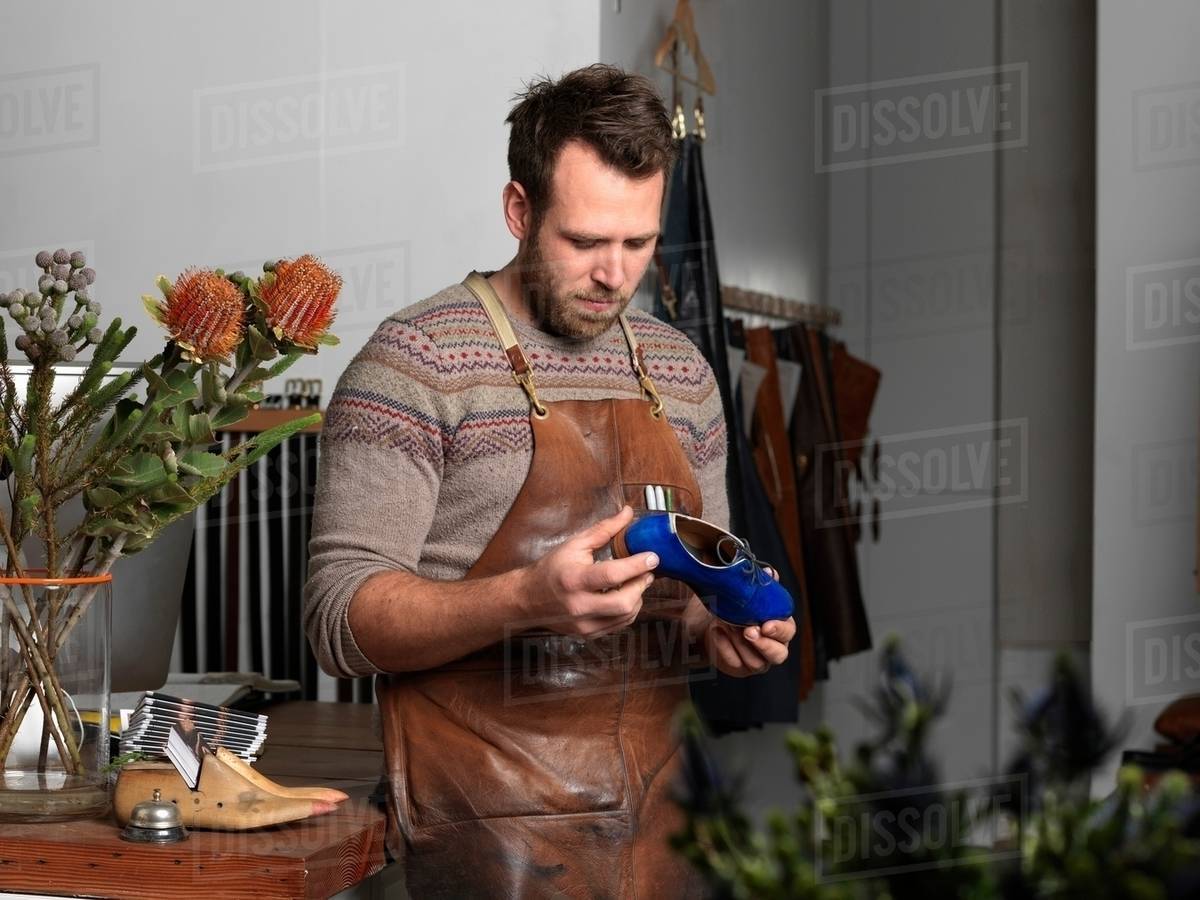 Shoemaker holding blue shoe in workshop - Royalty-free Stock Photo ...