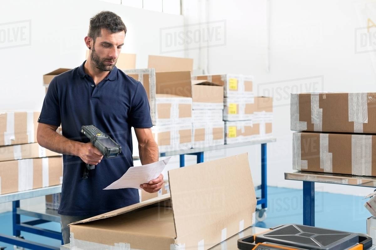 Warehouse worker scanning paperwork in distribution warehouse - Royalty ...