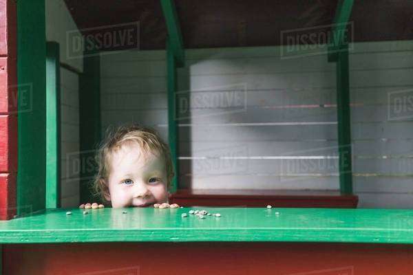 Portrait of young girl peering over ledge, smiling - Stock Photo - Dissolve