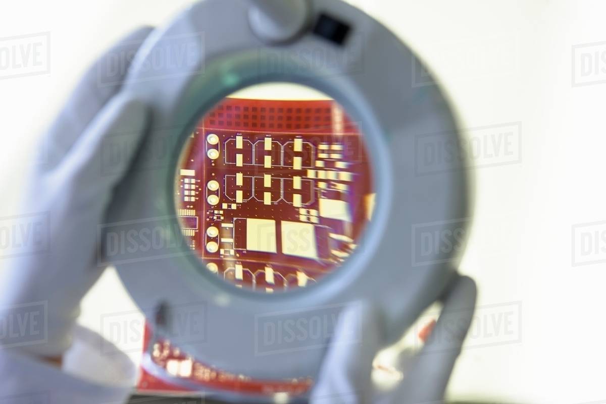 Red circuit board under inspection magnifier in circuit board factory ...