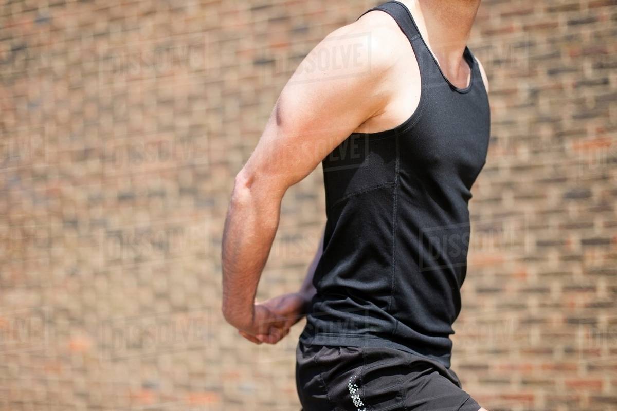 Runner stretching by brick wall - Royalty-free Stock Photo | Dissolve