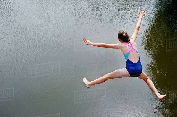 Overhead view of girl jumping into lake - Stock Photo - Dissolve