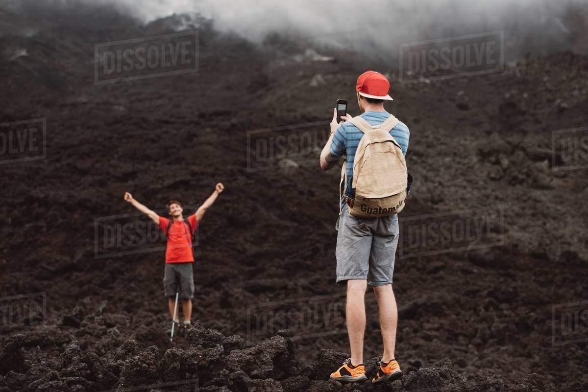 Young man photographing friend at Pacaya volcano, Antigua, Guatemala ...