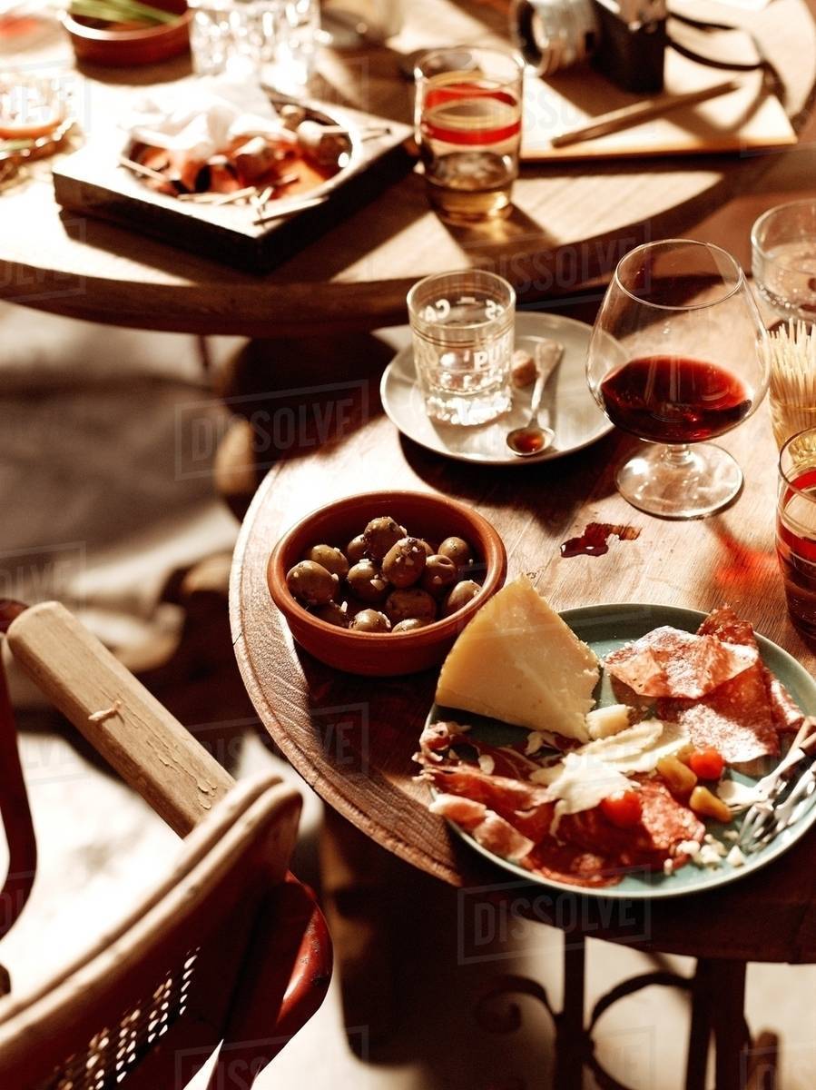 Tables with antipasto starters with olives, chorizo, salami, cheese ...