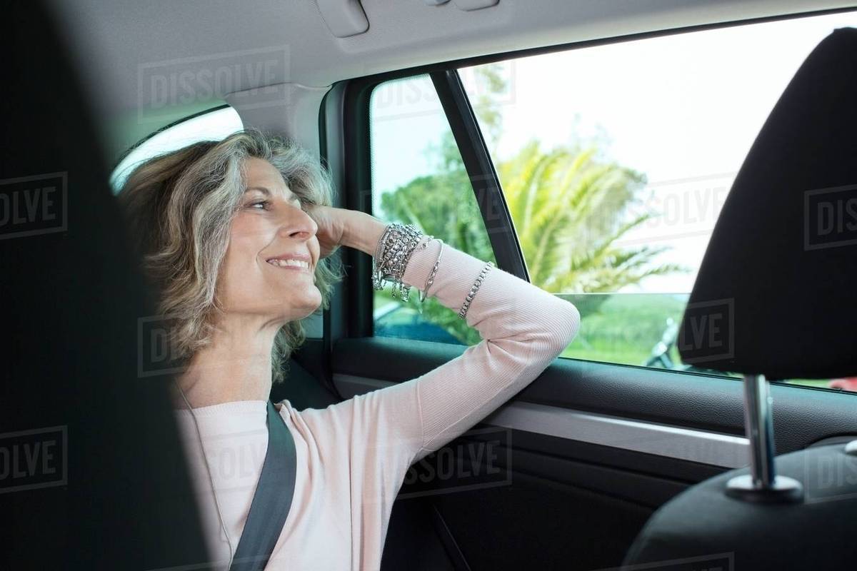 Senior businesswoman looking through car window - Stock Photo - Dissolve