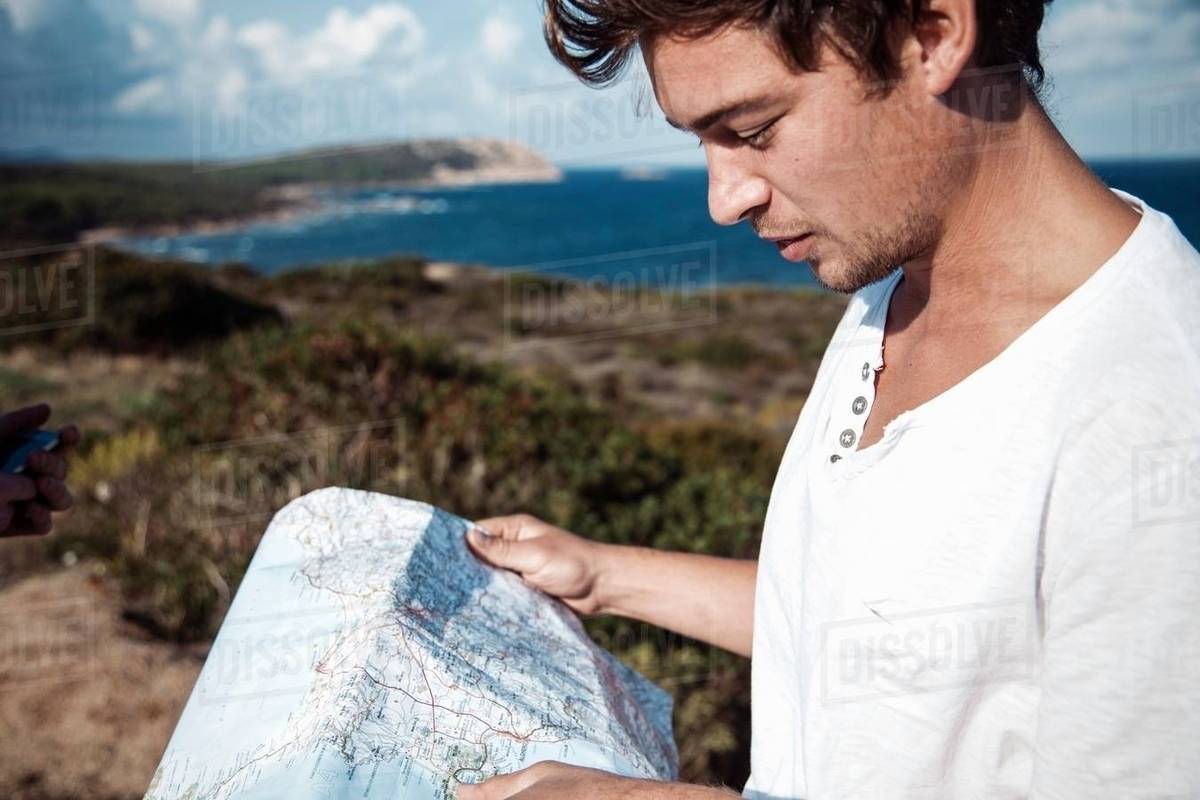 Cropped side view of young man looking down at map, Castelsardo ...