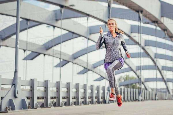 Female runner running at speed on city footbridge - Royalty-free Stock ...