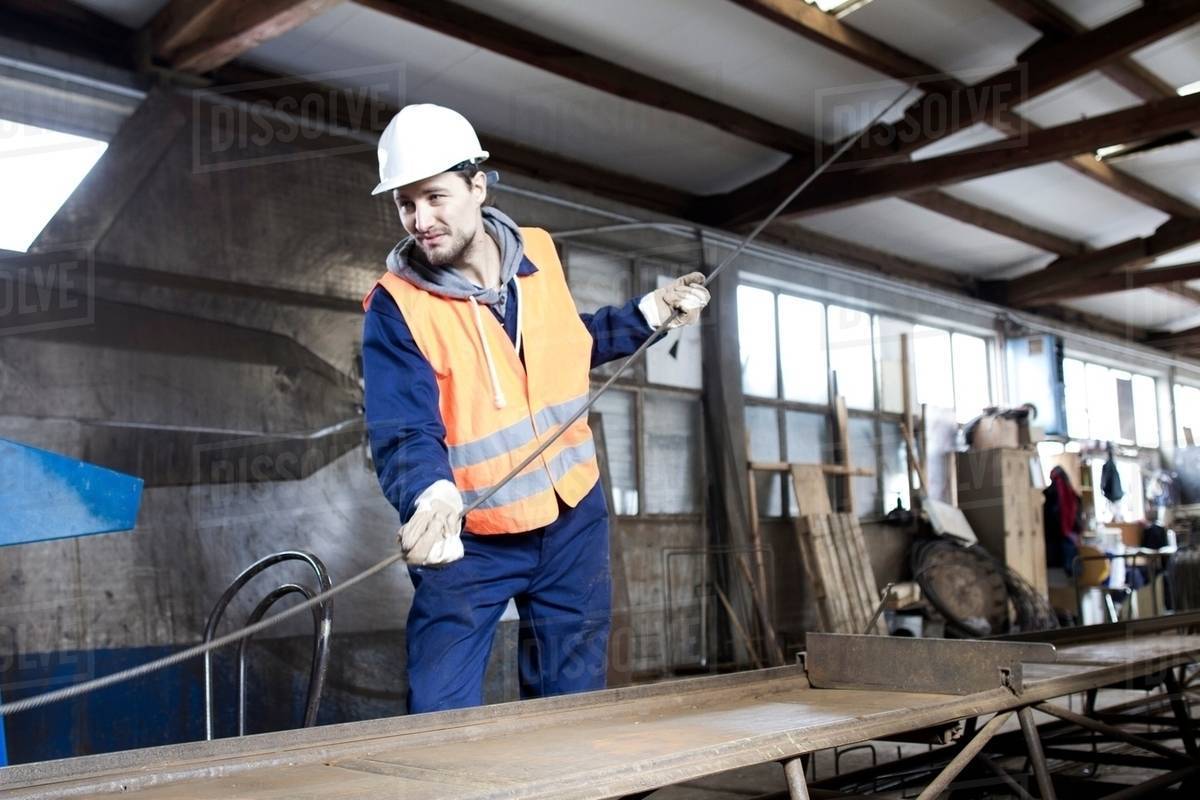 Factory worker moving steel rod at concrete reinforcement factory ...