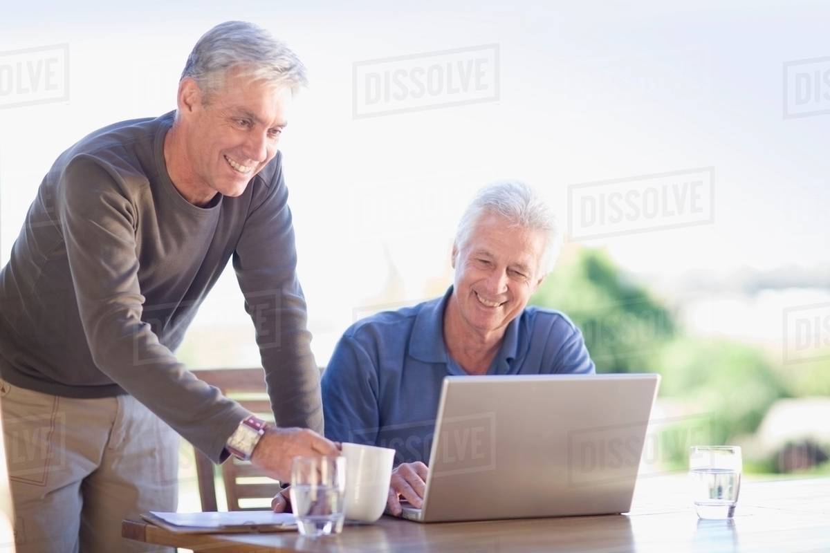 Older men using laptop together - Royalty-free Stock Photo | Dissolve
