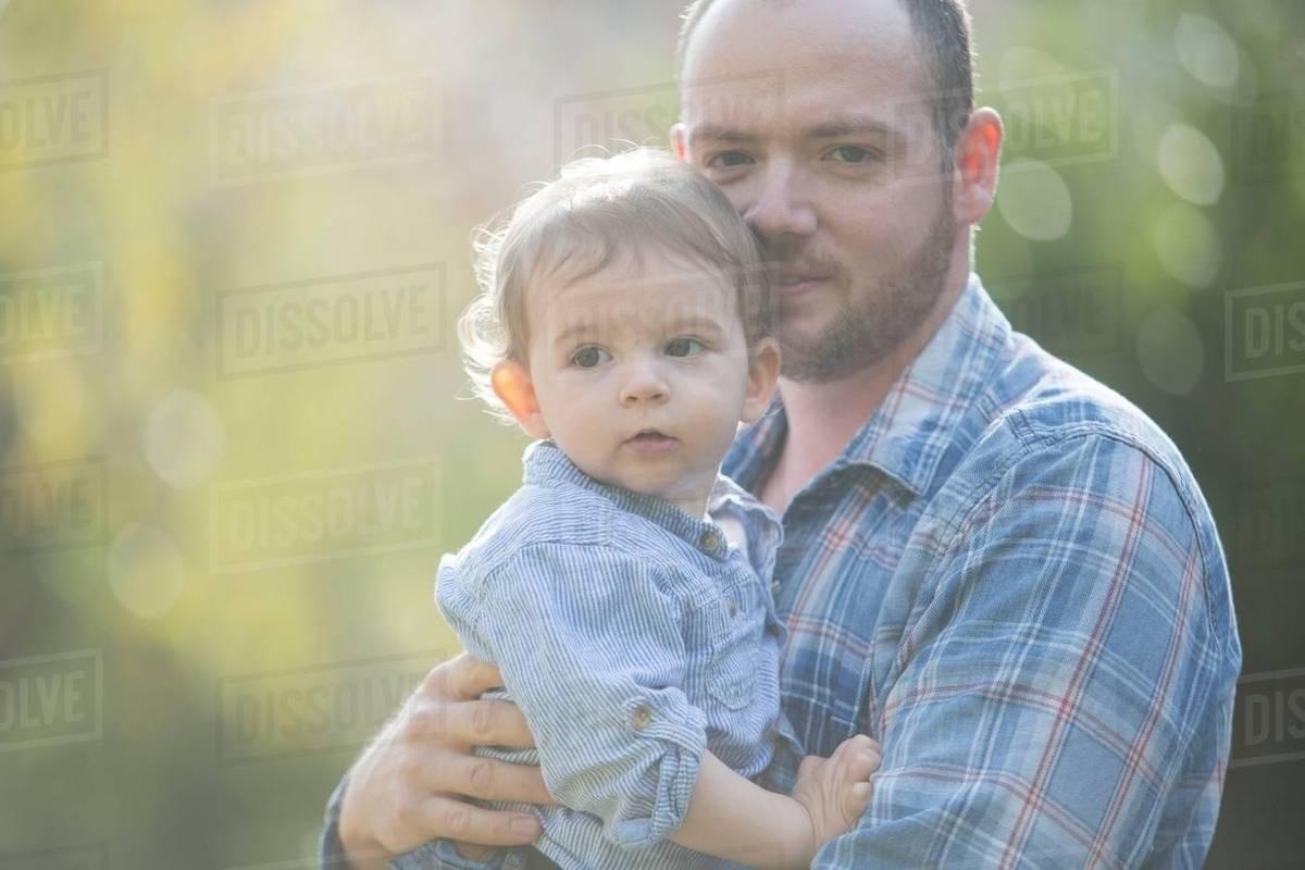 Father hugging baby boy, looking at camera - Royalty-free Stock Photo ...