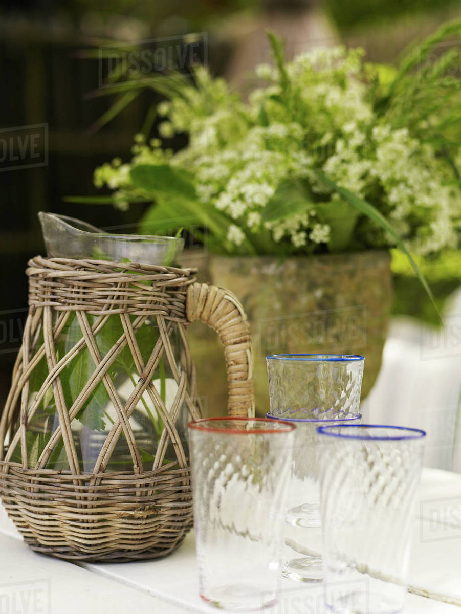 Vintage wicker jug and drinking glasses on garden table - Stock Photo ...