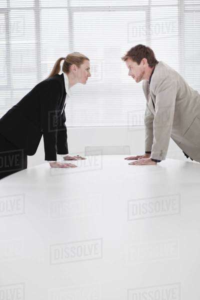 Rival business people leaning over desk - Royalty-free Stock Photo ...