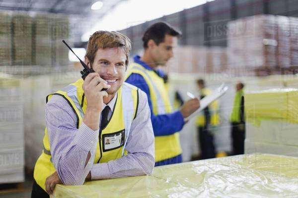 Worker using walkie talkie in warehouse - Stock Photo - Dissolve