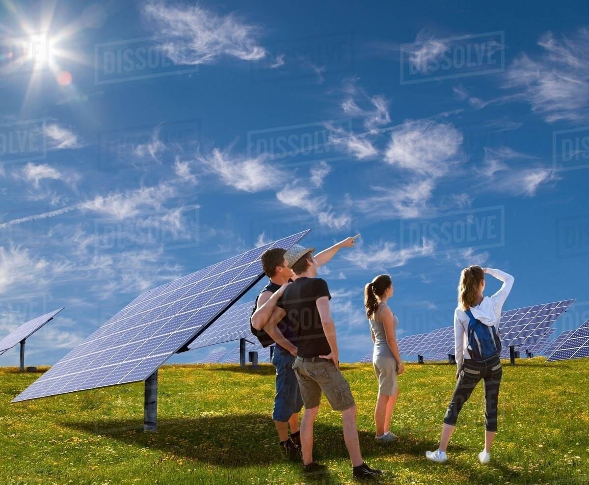 People standing in field by solar panels - Stock Photo - Dissolve