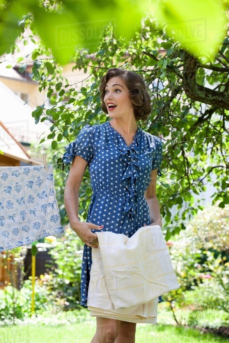 Woman folding sheet on clothesline - Royalty-free Stock Photo | Dissolve