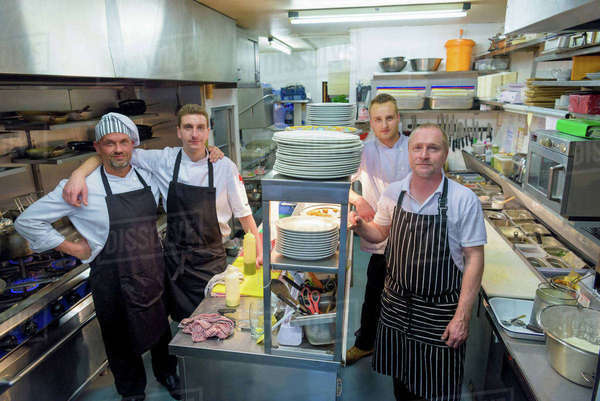 Portrait of chefs and kitchen workers in traditional Italian restaurant ...