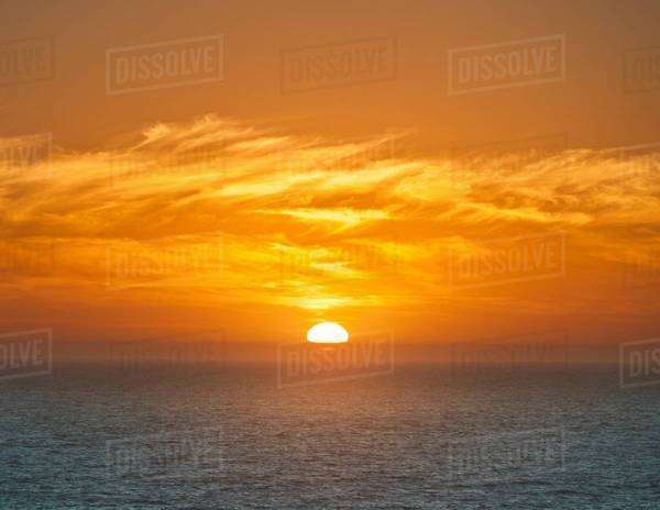 Sun setting over horizon - Stock Photo - Dissolve