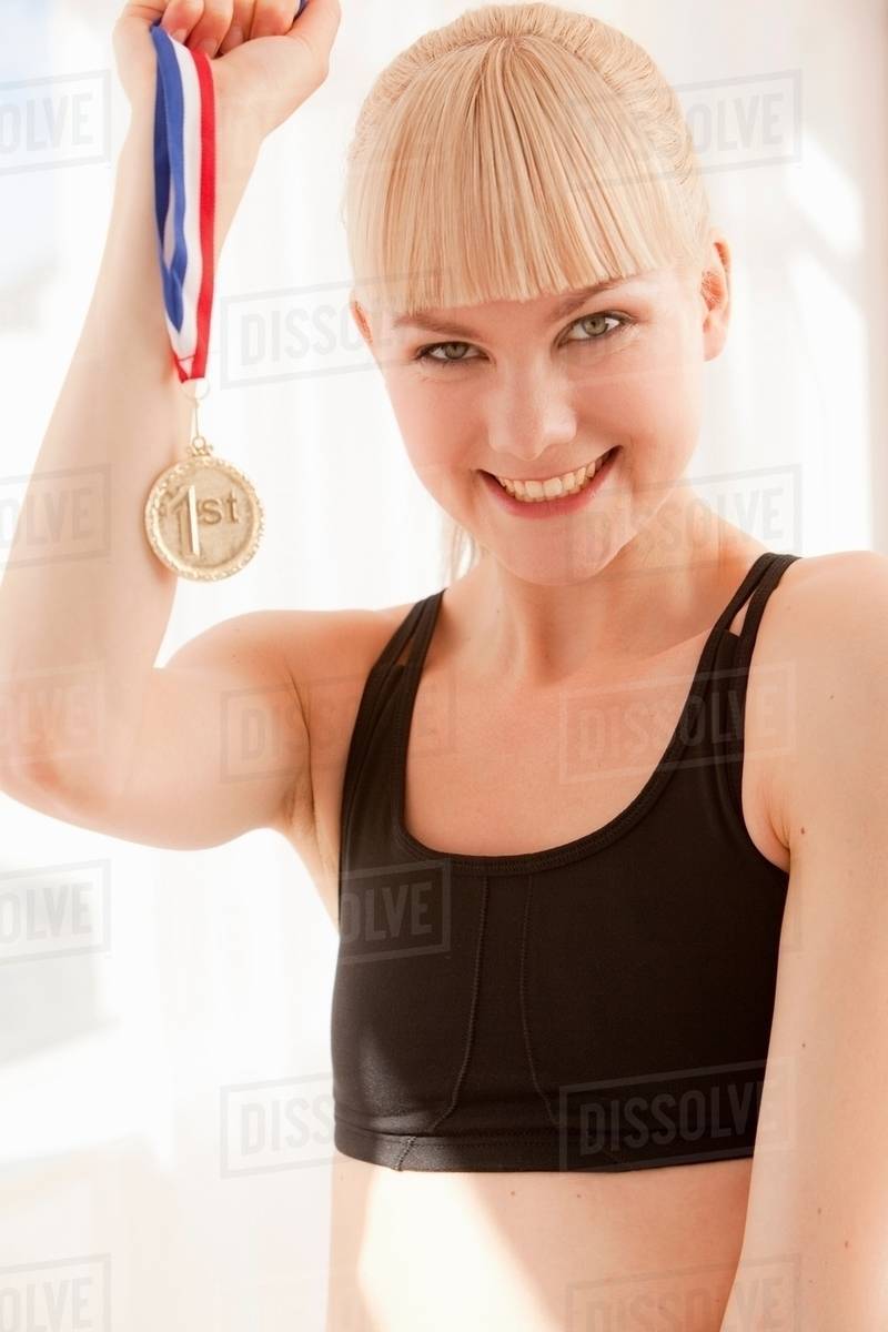 Cheering athlete holding gold medal - Stock Photo - Dissolve