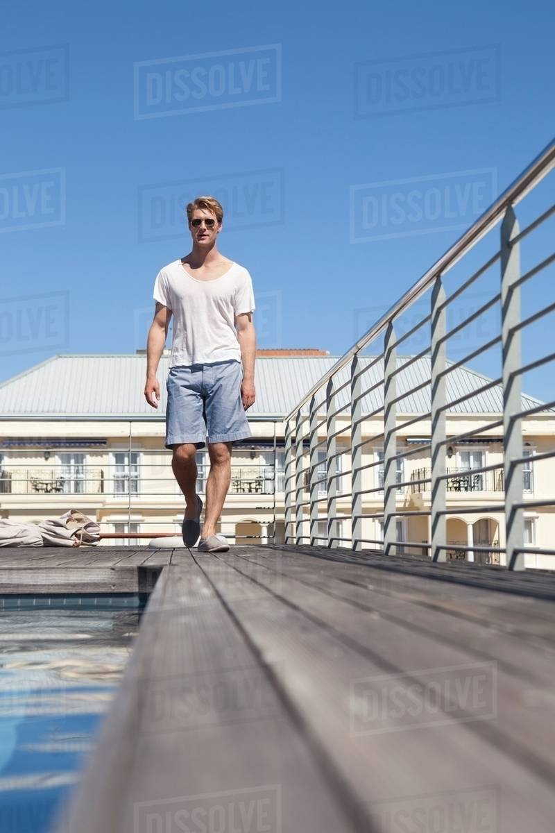 Man walking by swimming pool - Stock Photo - Dissolve