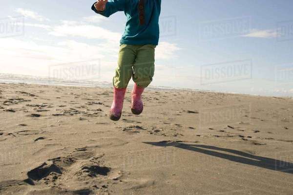 Young girl jumping on sandy beach - Stock Photo - Dissolve