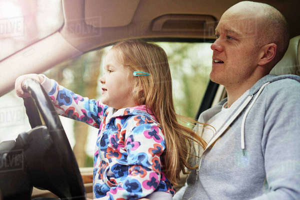 Daughter sitting on father lap driving car - Royalty-free Stock Photo ...