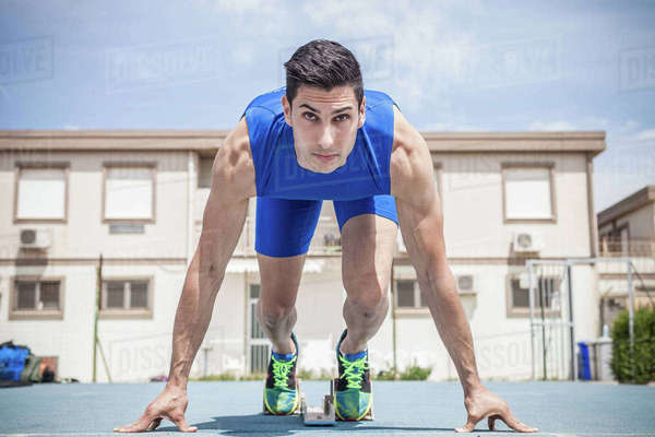 Young male sprinter on his marks on running track - Stock Photo - Dissolve