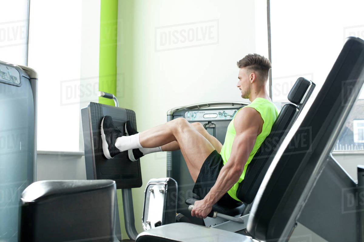 Side view of young man in gym using exercise equipment - Royalty-free ...