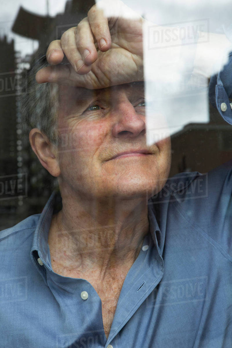 Man smiling and leaning head against window - Stock Photo - Dissolve