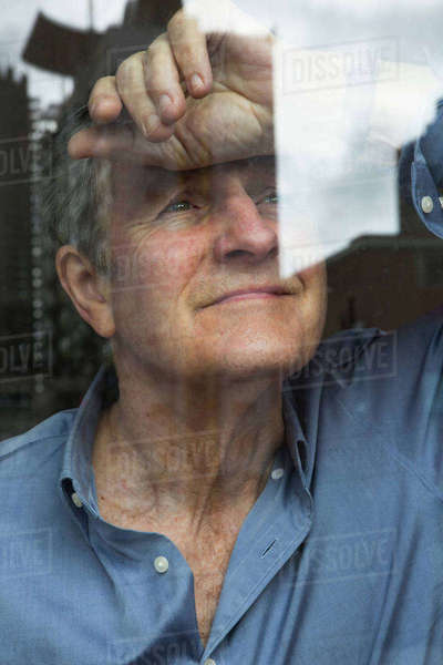 Man smiling and leaning head against window - Stock Photo - Dissolve