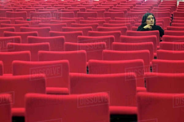 Woman sitting alone in hall of empty red seats - Royalty-free Stock ...