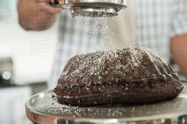 Man sieving icing sugar over cake - Royalty-free Stock Photo | Dissolve