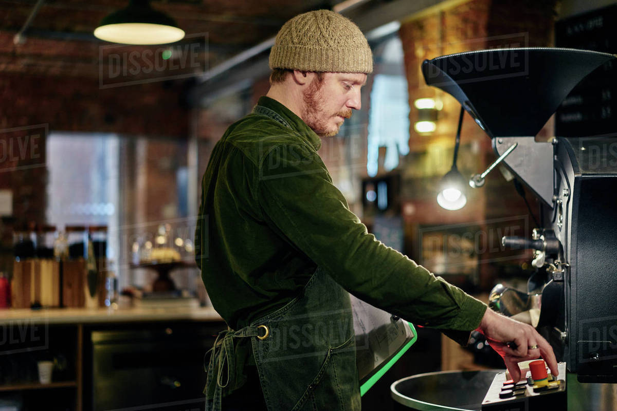 Male coffee shop owner using coffee roaster - Stock Photo - Dissolve