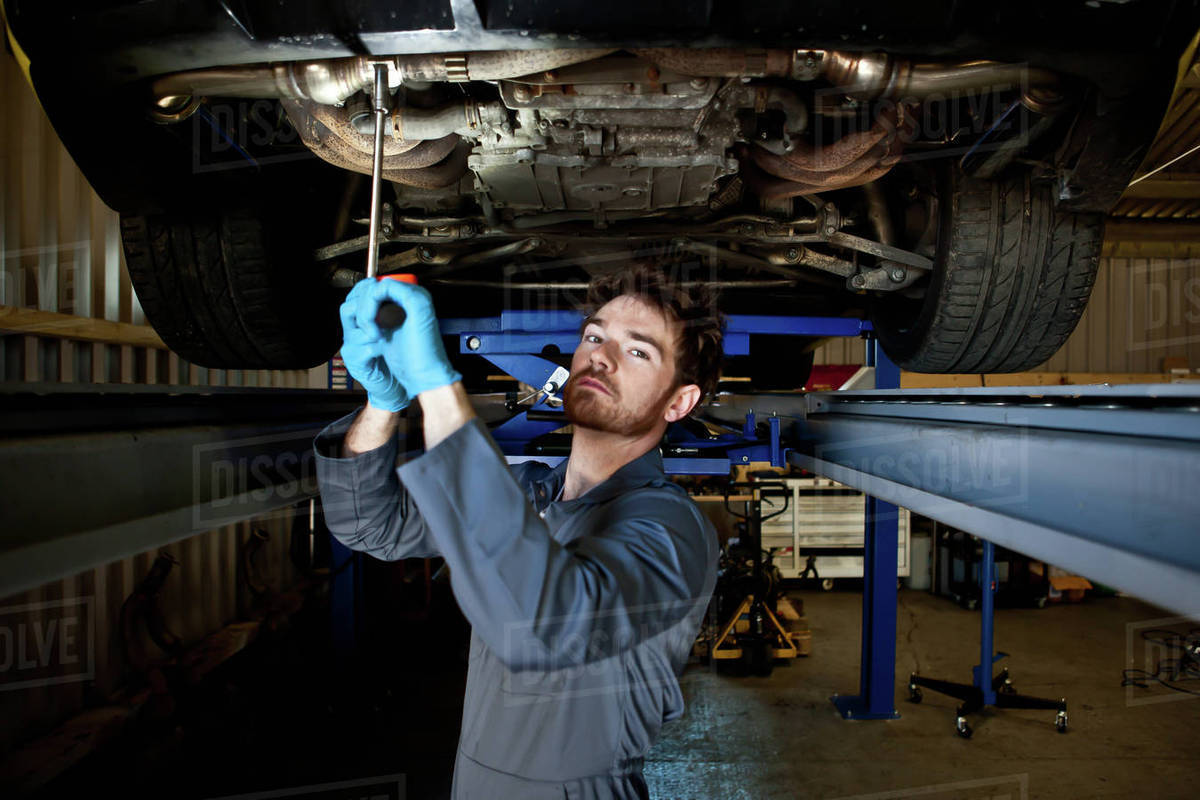 Male mechanic doing maintenance under car - Stock Photo - Dissolve