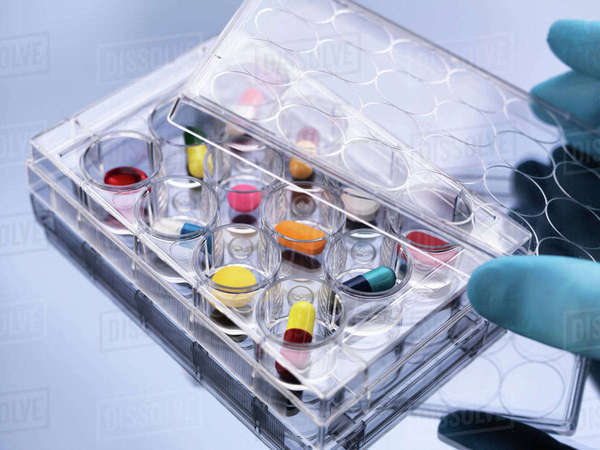 Pharmaceutical research, hand removing lid from variety of medical ...