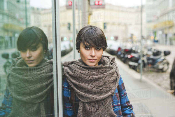 Portrait of young woman leaning against window, outdoors - Stock Photo ...