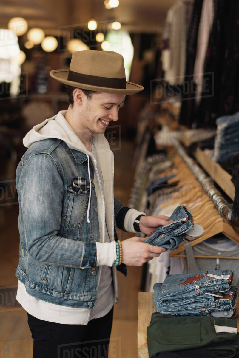 Young man looking at clothes in clothes shop - Stock Photo - Dissolve