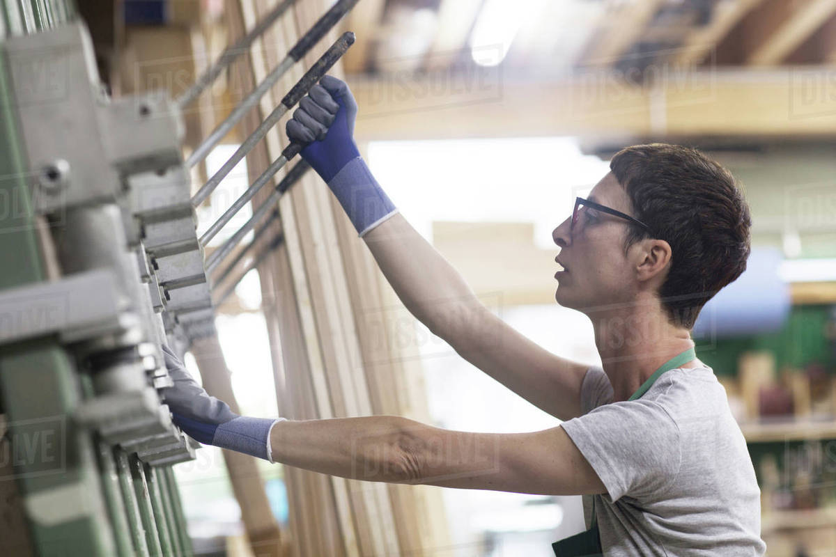 Side view of woman in workshop pulling lever - Royalty-free Stock Photo ...