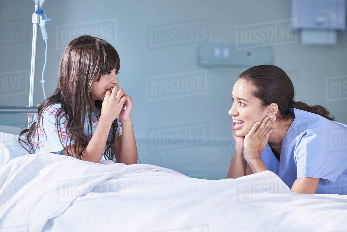 Girl patient talking to female nurse in hospital children's ward ...