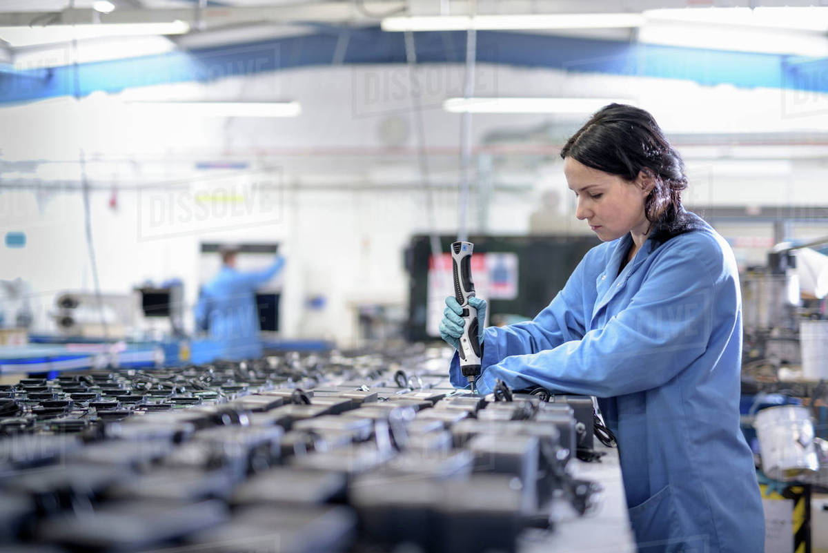 Female worker assembling components in circuit board assembly factory ...