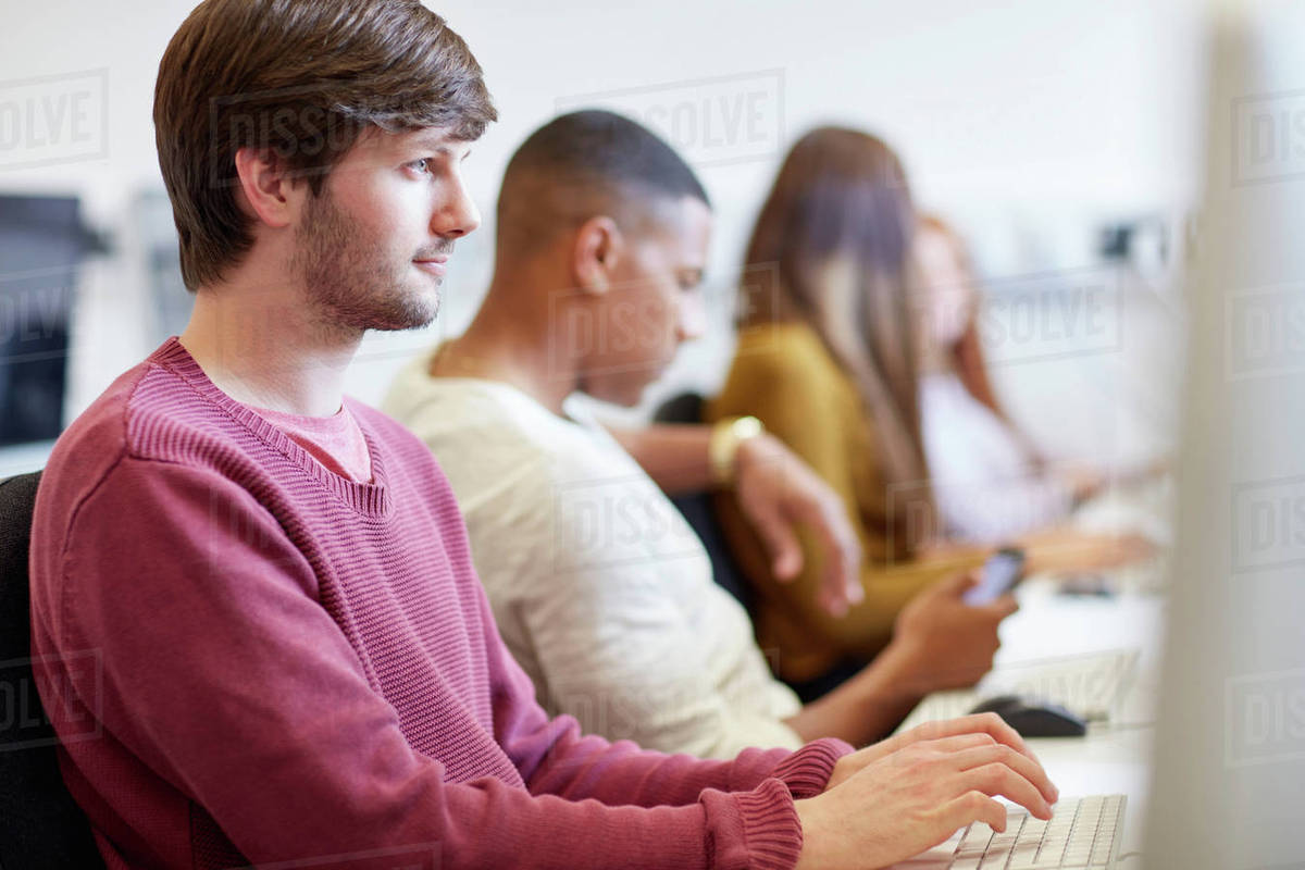 Students typing on computers in higher education college computer room ...