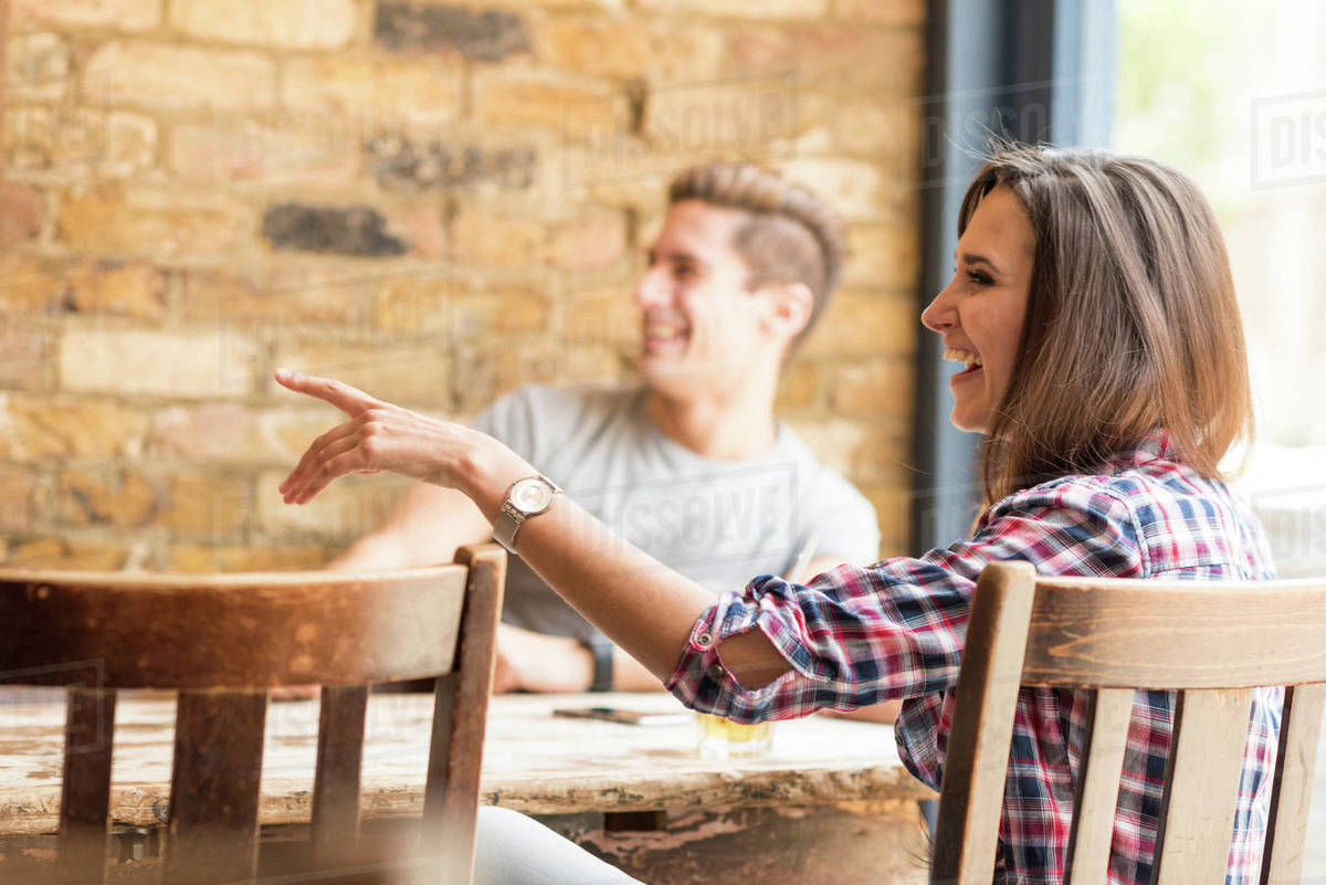 Young couple pointing in bar - Royalty-free Stock Photo | Dissolve